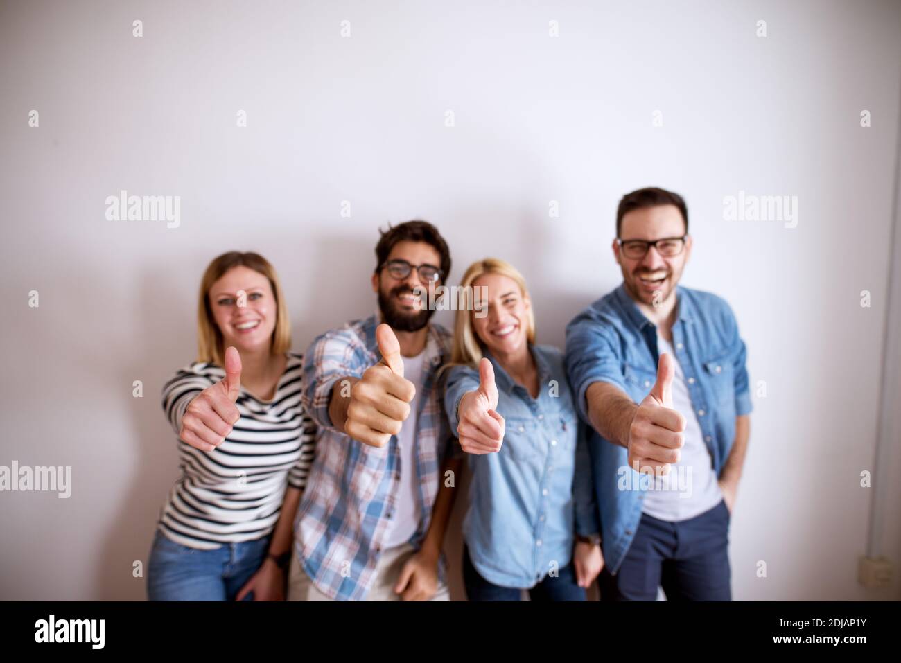 Group of young smiling business people extending arms showing thumbs up ...