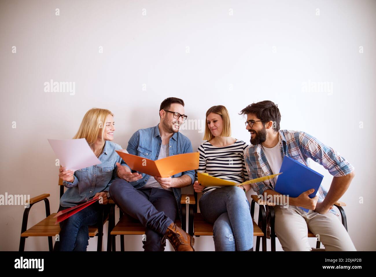 Group of young joyful satisfied friends holding colourful folder while ...