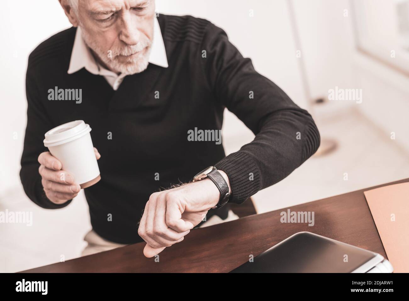 Senior businessman checking time on his wrist watch Stock Photo - Alamy