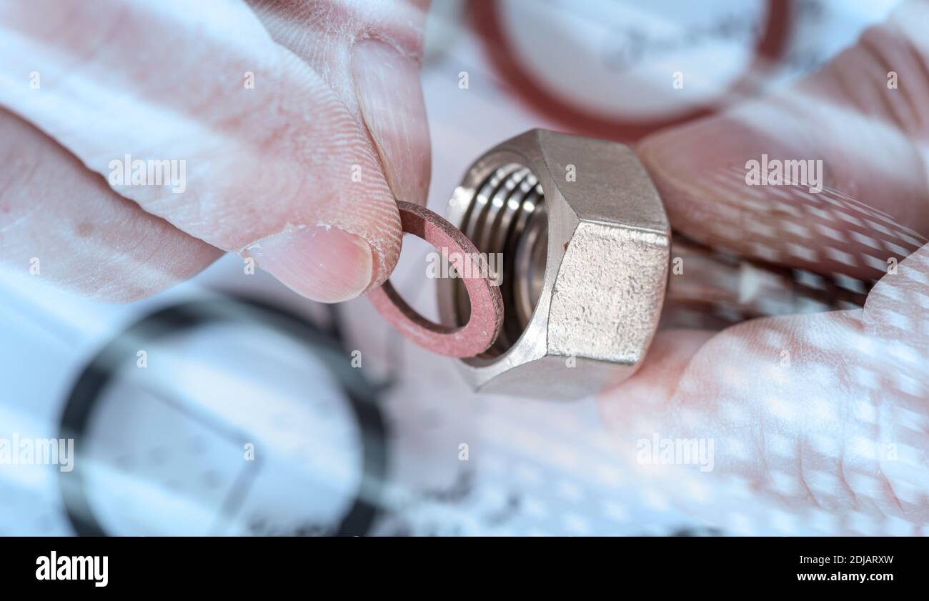 Plumber putting a gasket on a plumbing fitting, closeup; light effect ...