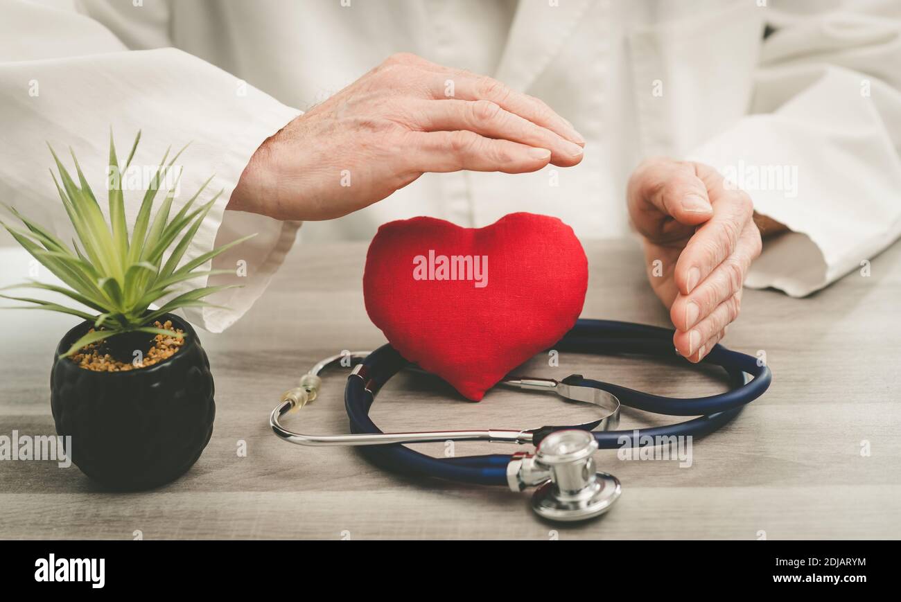 Hands of doctor protecting a red heart Stock Photo - Alamy