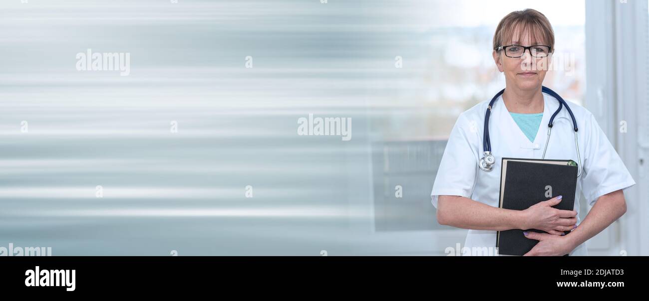 Portrait of female doctor standing and holding a medical textbook ...