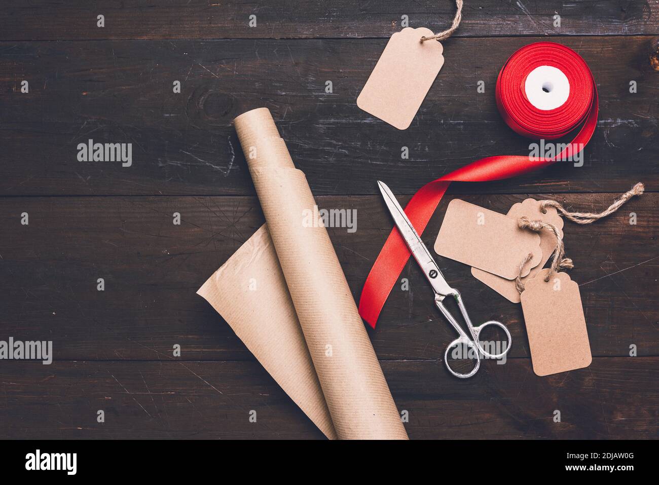 roll of brown kraft packaging paper, red silk ribbon, scissors and a ...