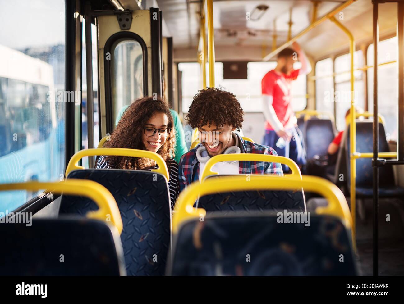 Young happy gorgeous couple is sitting together in a bus and smiling ...