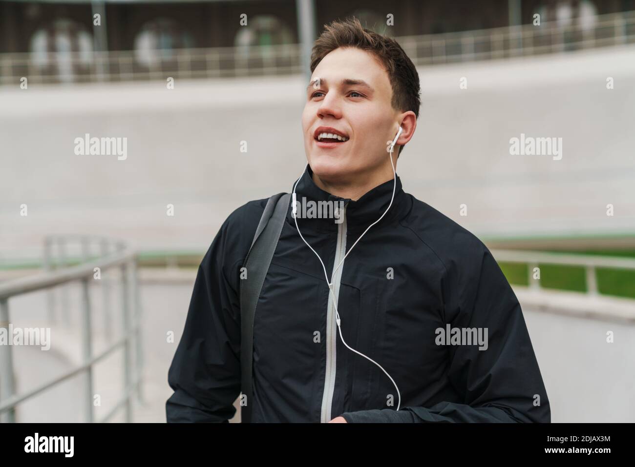 Happy young sportive man walking on stadium, carrying sport bag Stock ...