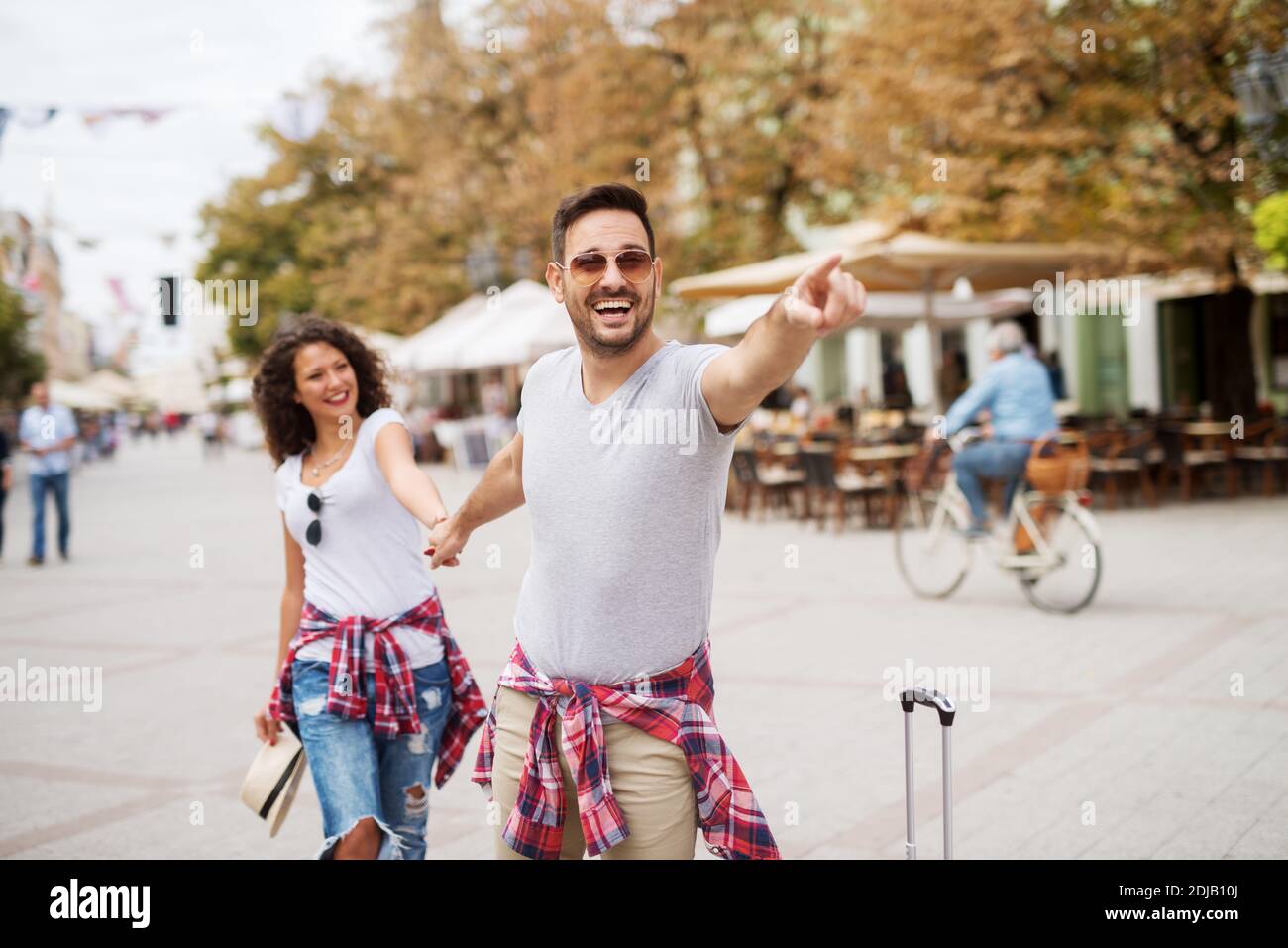 Handsome man is leading his gorgeous young girlfriend by the hand and ...