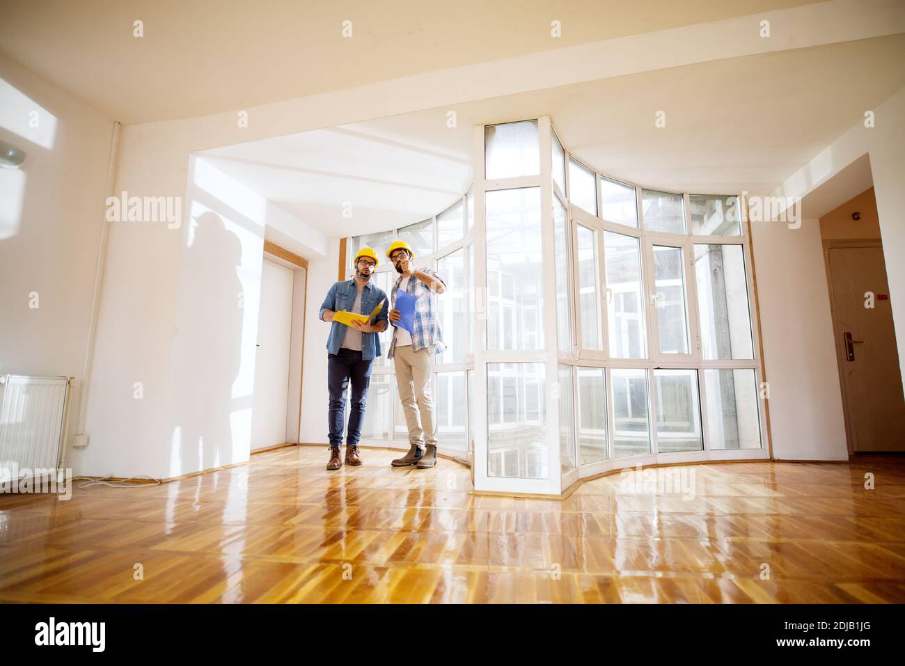 Two young focused engineers looking at and analyzing their plans ...