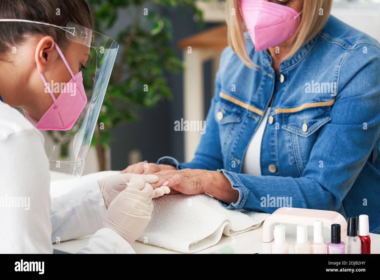 Senior lady wearing a mask in manicure salon Stock Photo - Alamy