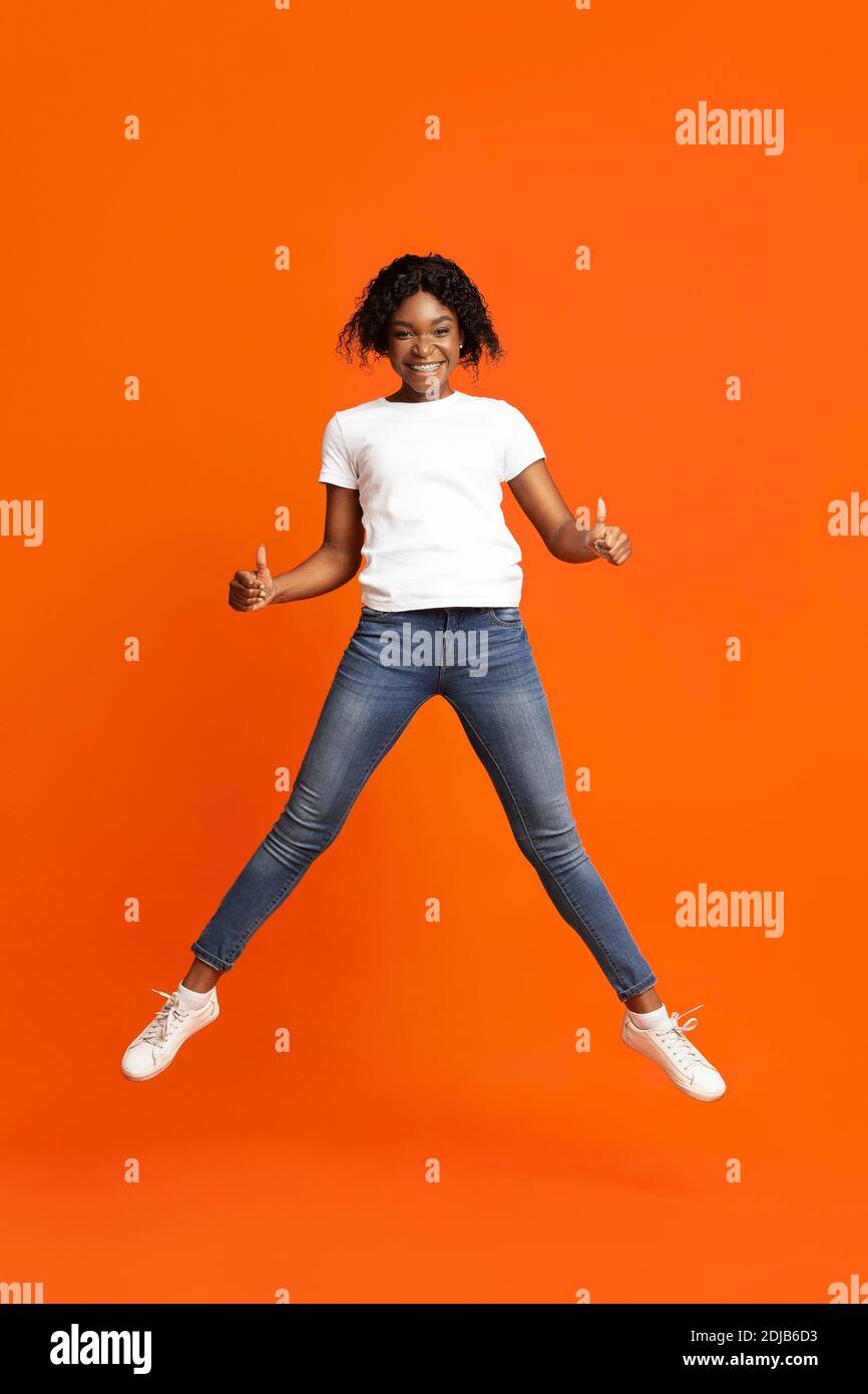 African-american joyful lady jumping and showing thumb up Stock Photo ...