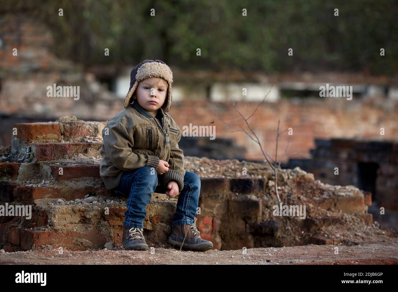 Cute child, posing in a ruin brick house, sitting on a window shield ...