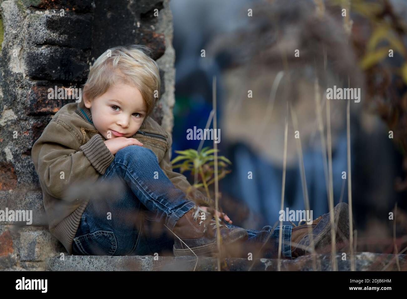 Cute child, posing in a ruin brick house, sitting on a window shield ...