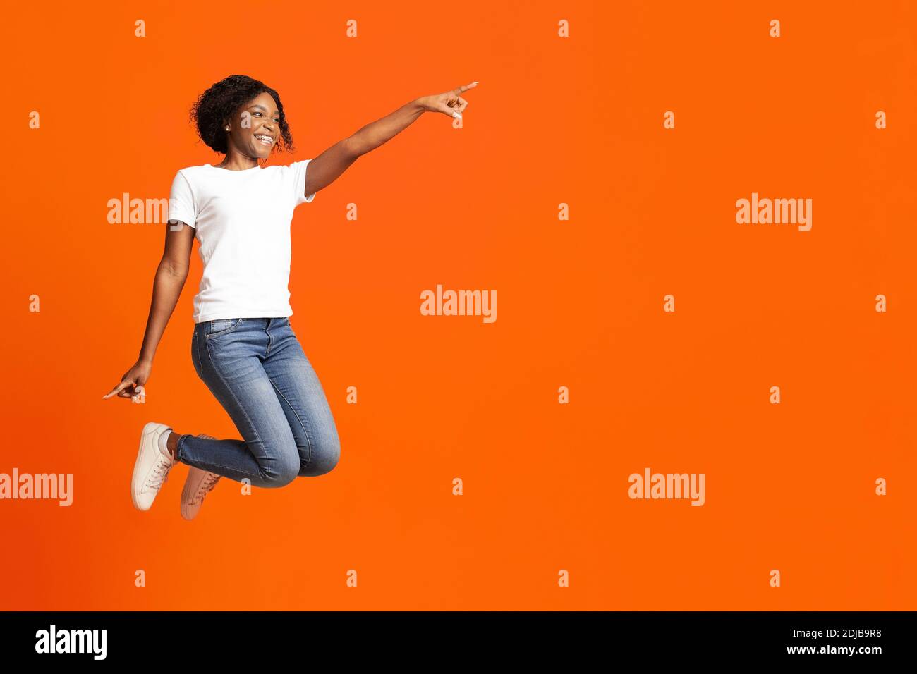 Excited black woman jumping up and showing copy space Stock Photo - Alamy
