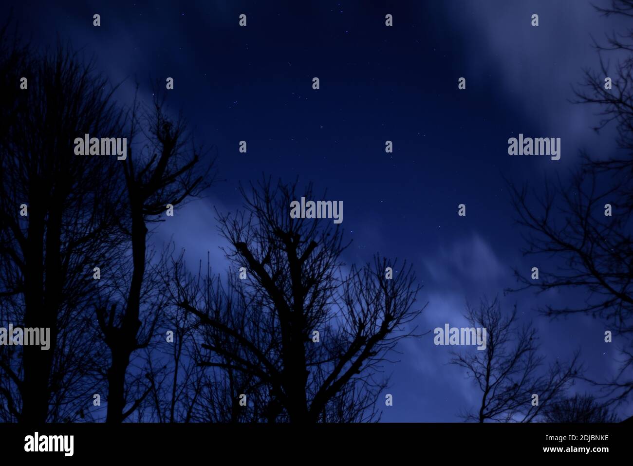 View of stars in a clear night sky with motion in clouds moving acroos ...