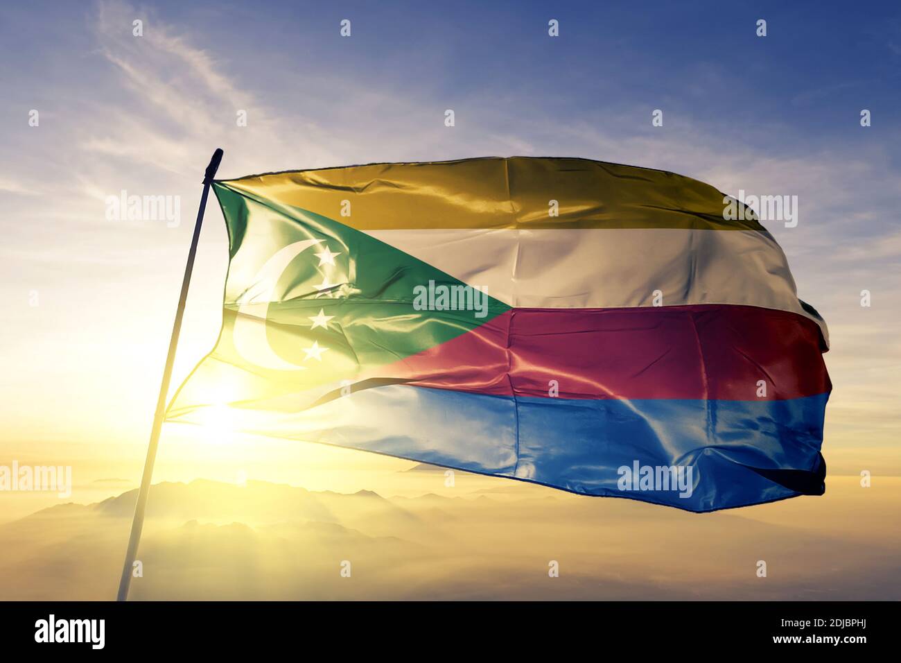 Comoros flag waving on the top sunrise mist fog Stock Photo - Alamy