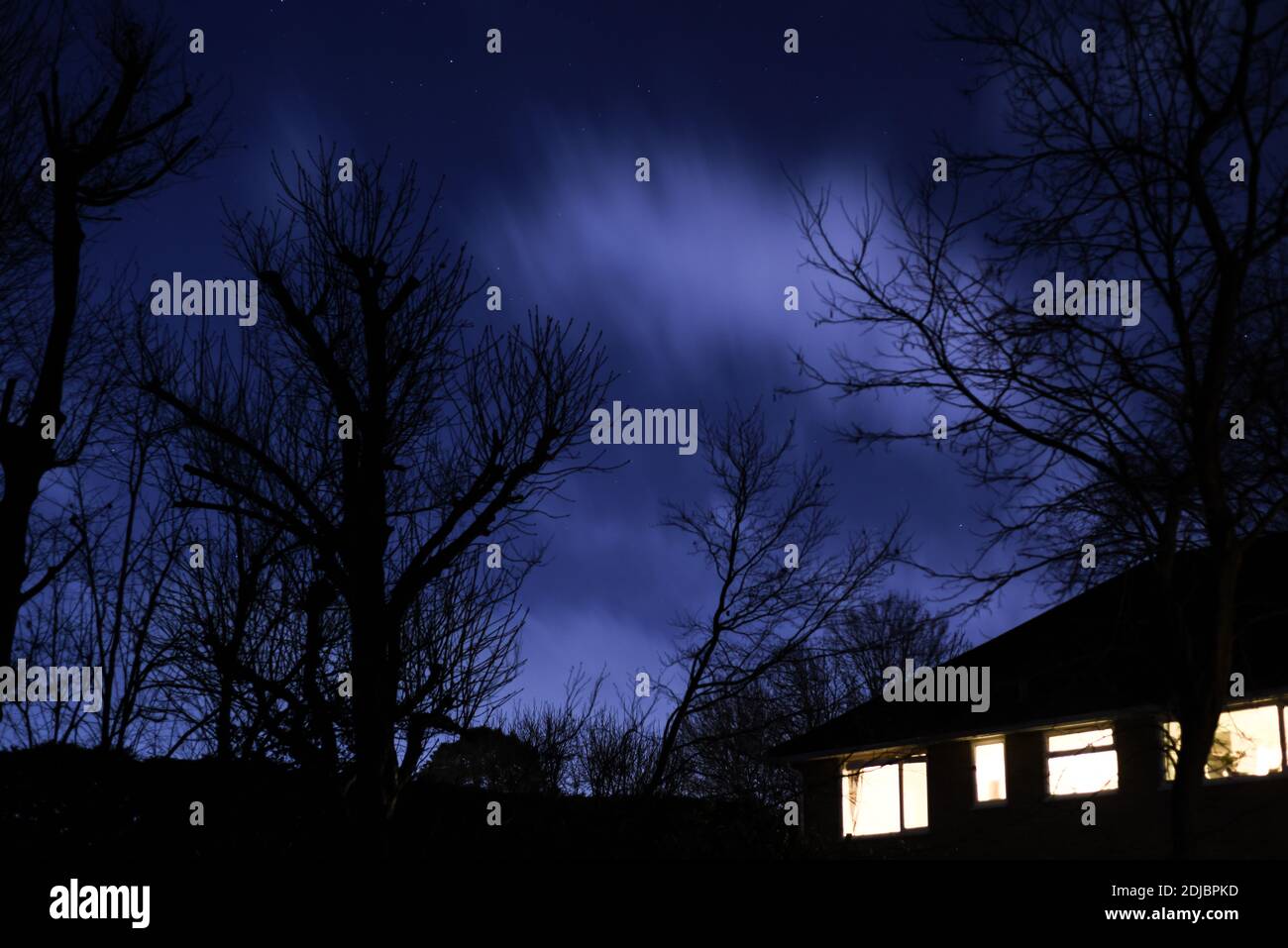 View of stars in a clear night sky with motion in clouds moving acroos ...