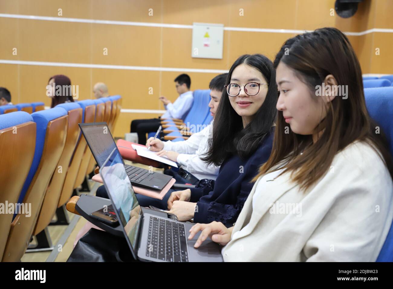 Asian female and male college students discuss over a computer while ...