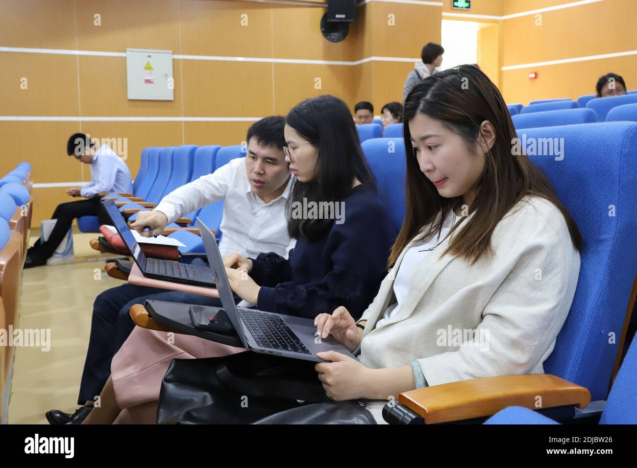 Asian female and male college students discuss over a computer while ...