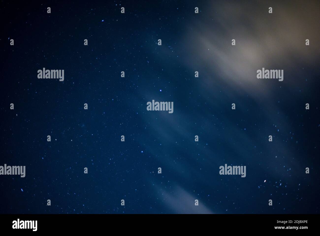 View of stars in a clear night sky with motion in clouds moving acroos ...