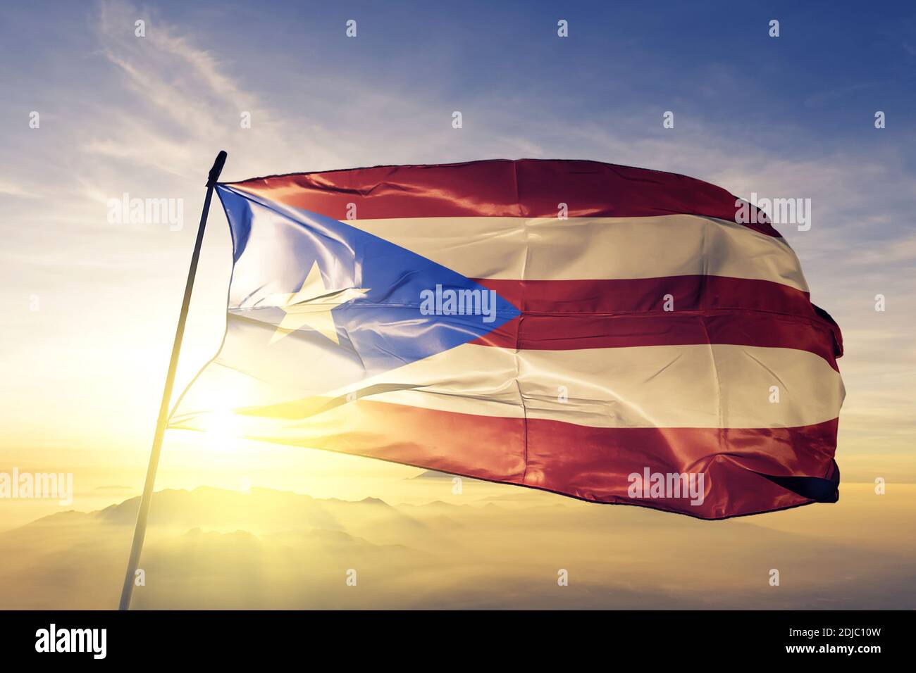 Puerto Rico flag waving on the top sunrise mist fog Stock Photo - Alamy