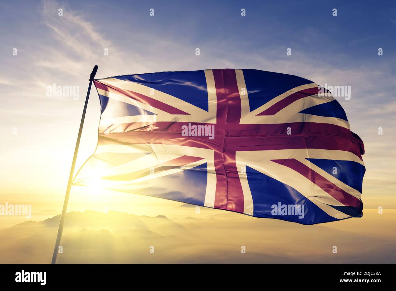 United Kingdom flag waving on the top sunrise mist fog Stock Photo - Alamy