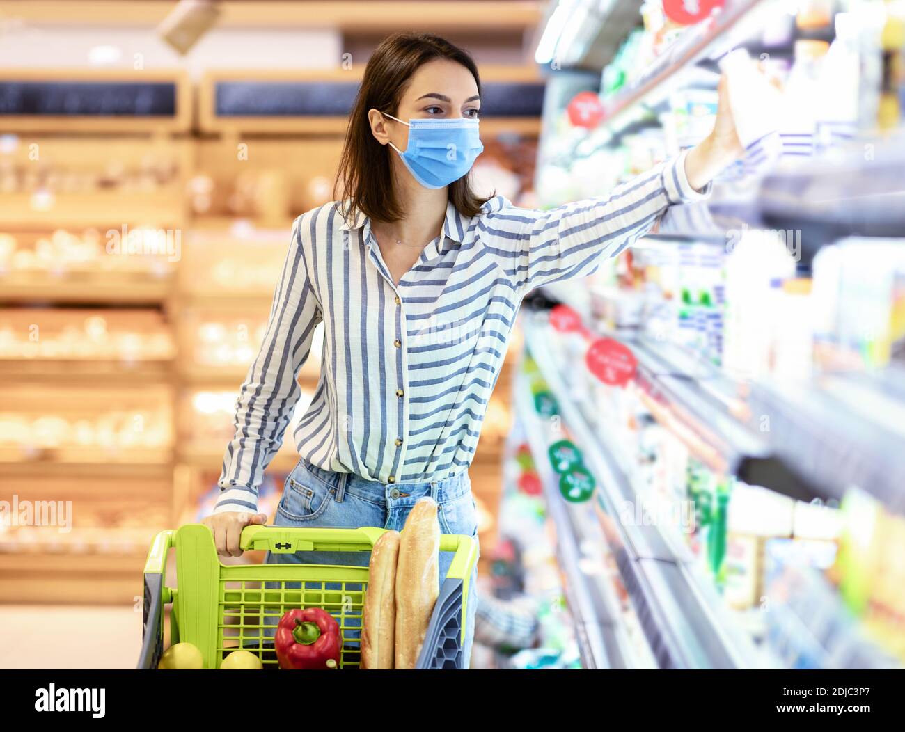 Woman in face mask shopping in supermarket with cart Stock Photo - Alamy