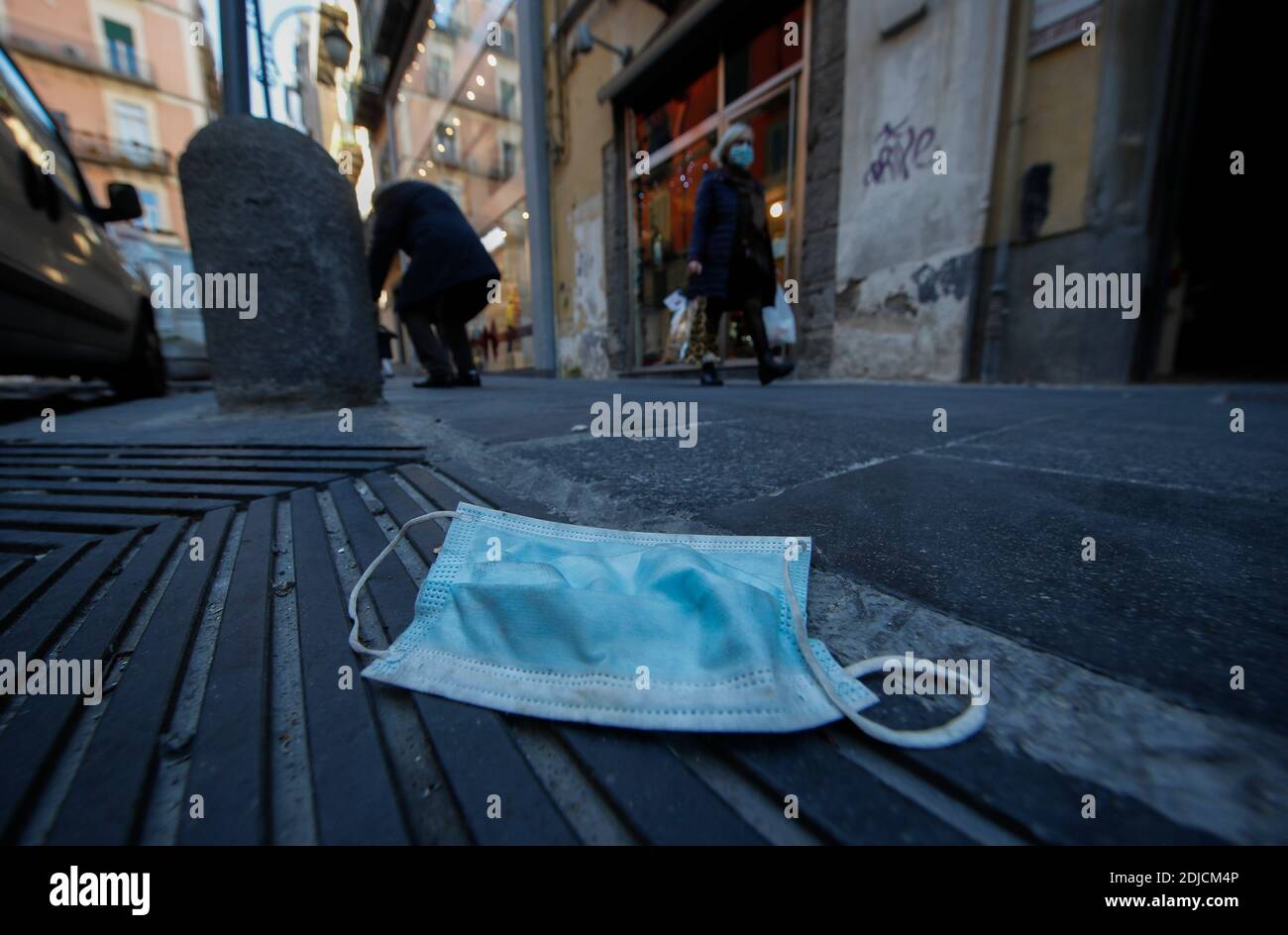 An obviously worn-out mouth and nose protection mask lies thrown away ...