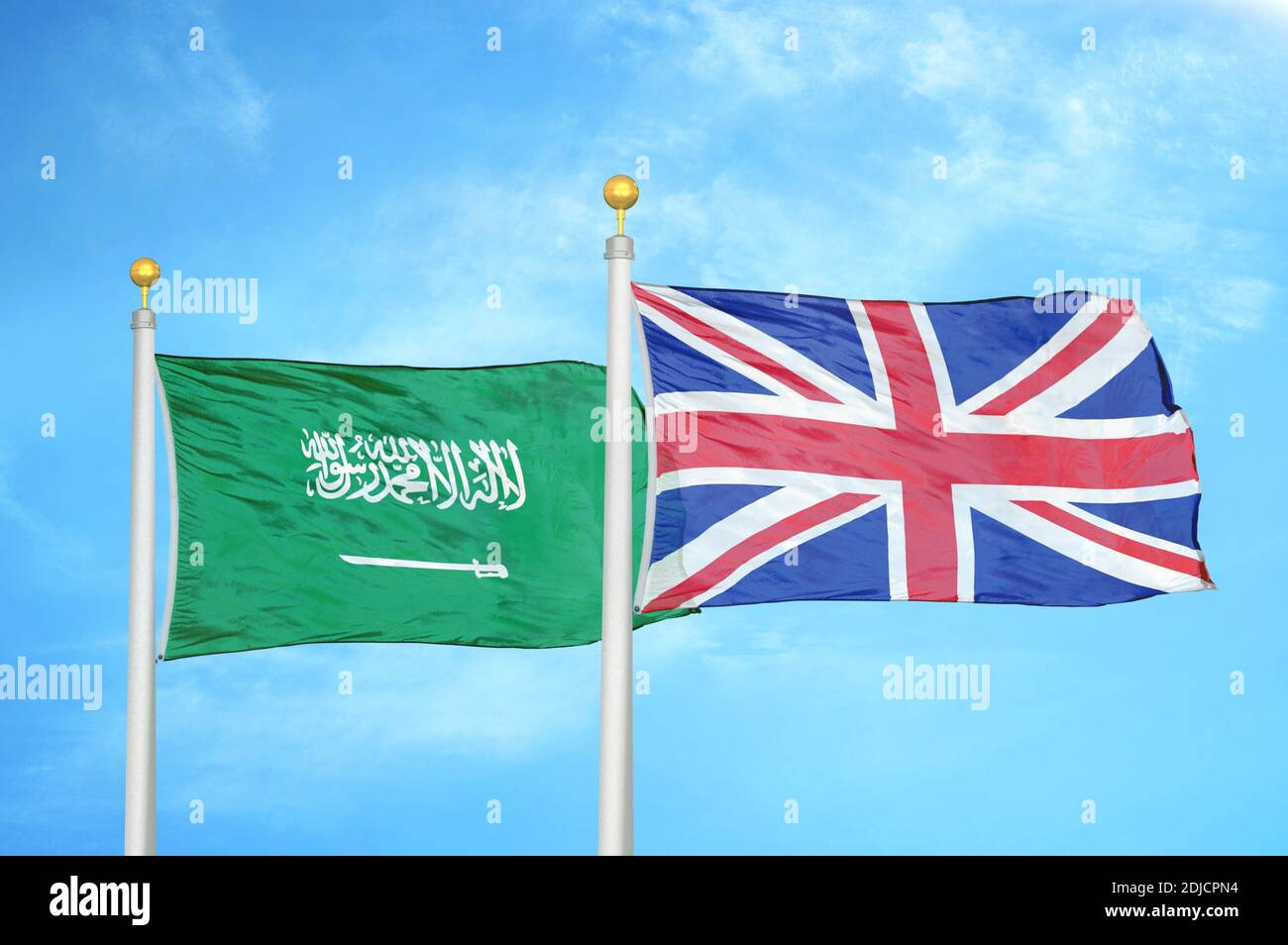 Saudi Arabia and United Kingdom two flags on flagpoles and blue cloudy ...