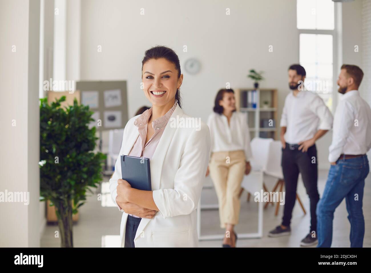 Cheerful female executive manager standing in office after meeting ...