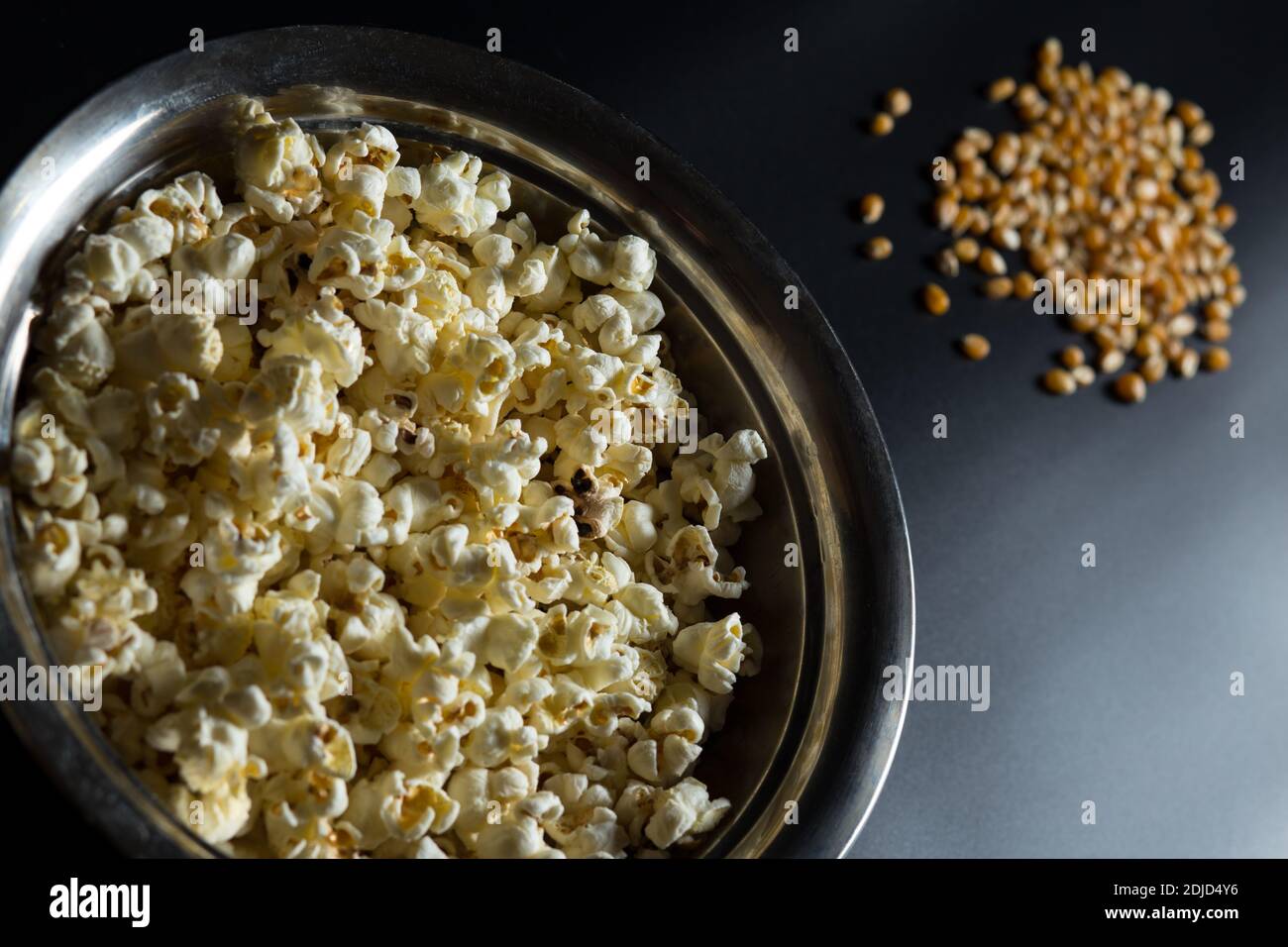 Portion of fried pocorn on bucket and raw seeds of popcorn, on black ...