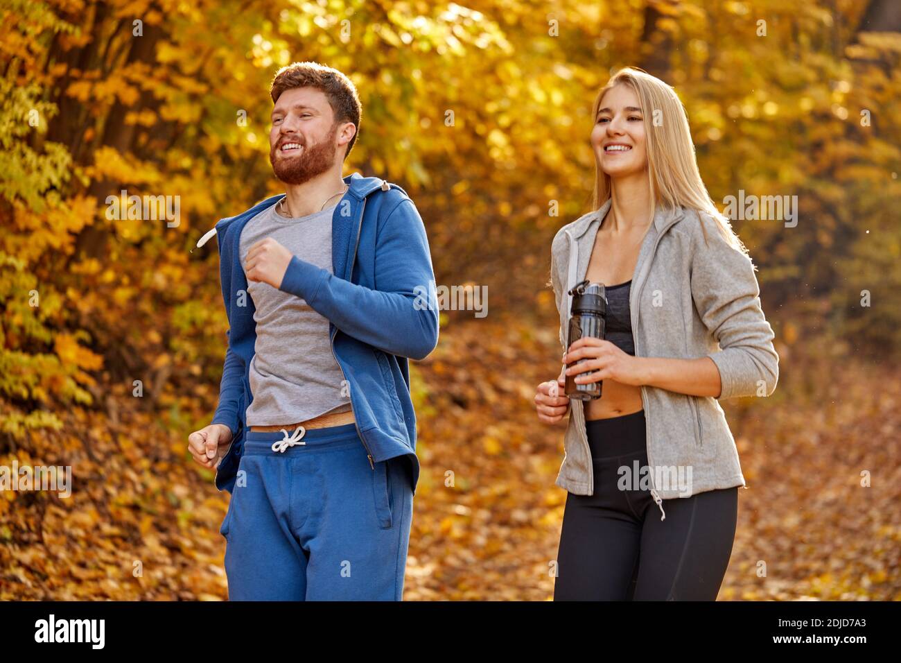couple running at autumn forest trail, young caucasian fit man and ...