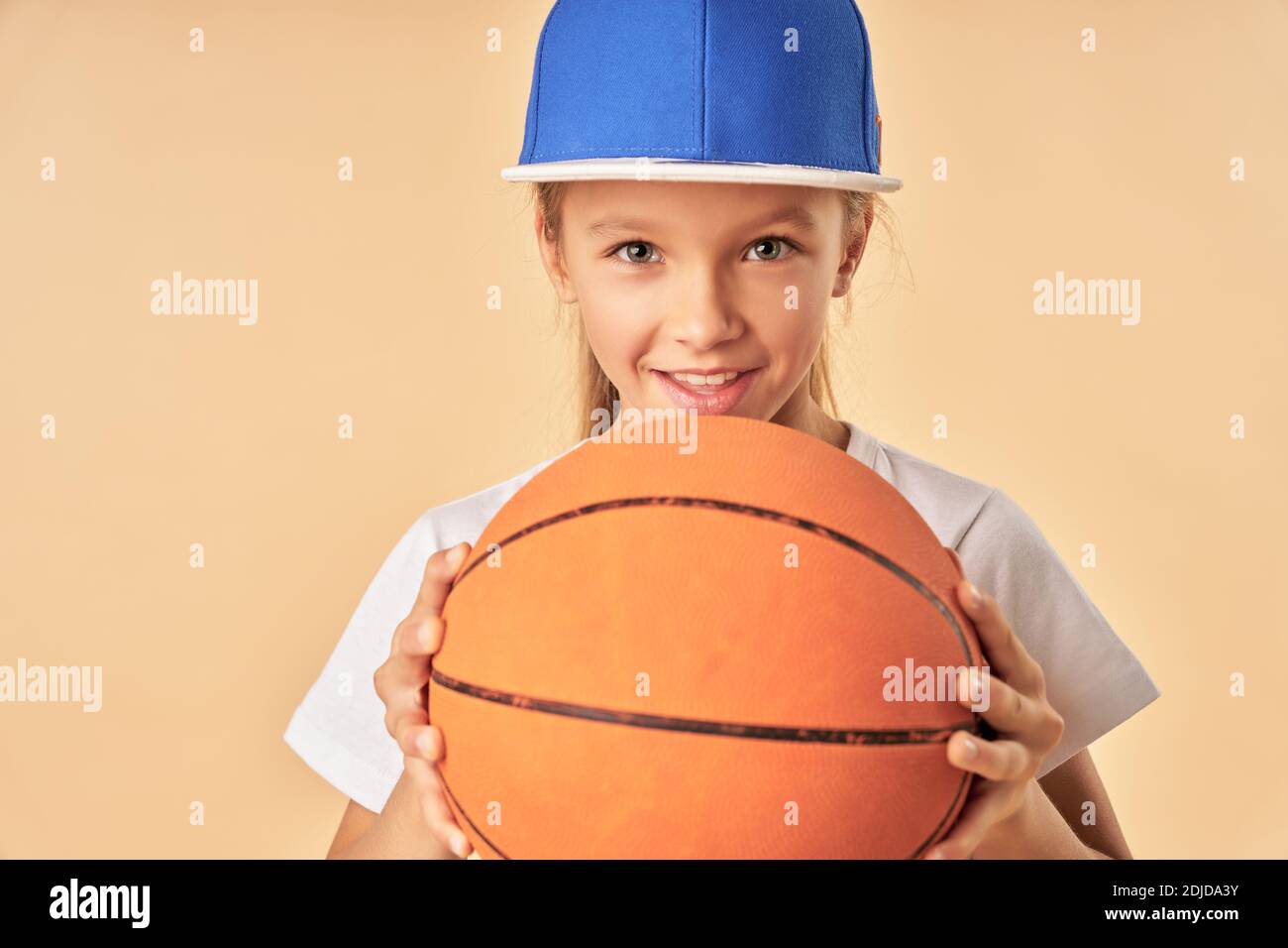 Cheerful female child basketball player holding game ball and smiling ...