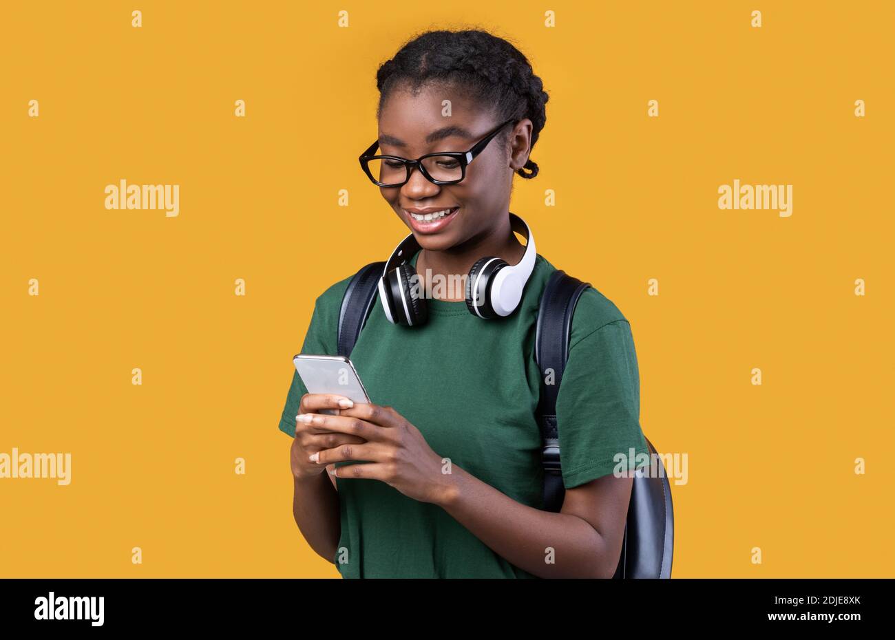Happy African Female Student Using Smartphone Standing Over Yellow ...