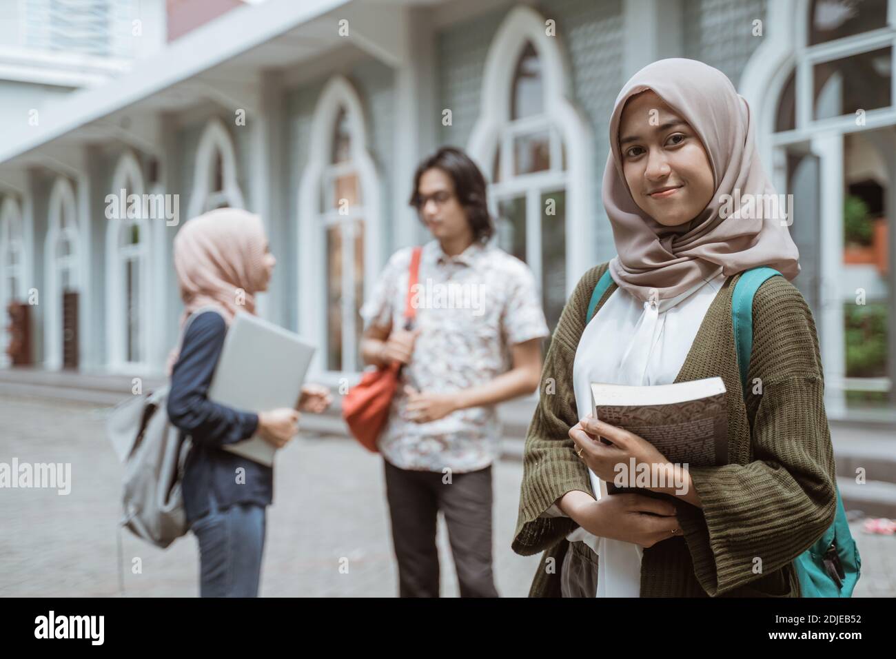 Portrait happy students looking at the camera on the campus yard. With ...