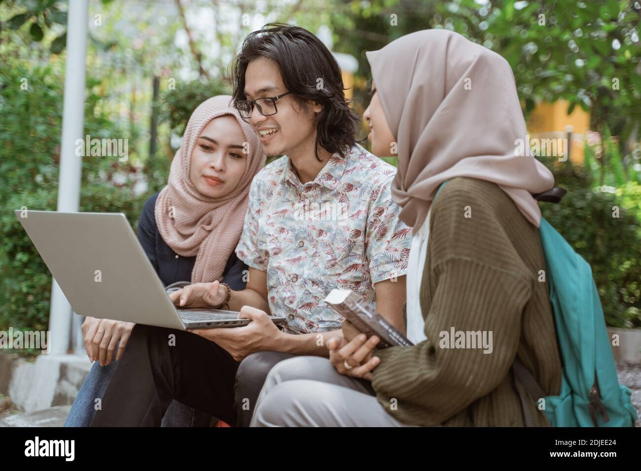 Portrait students discussing together with laptop on the campus yard ...