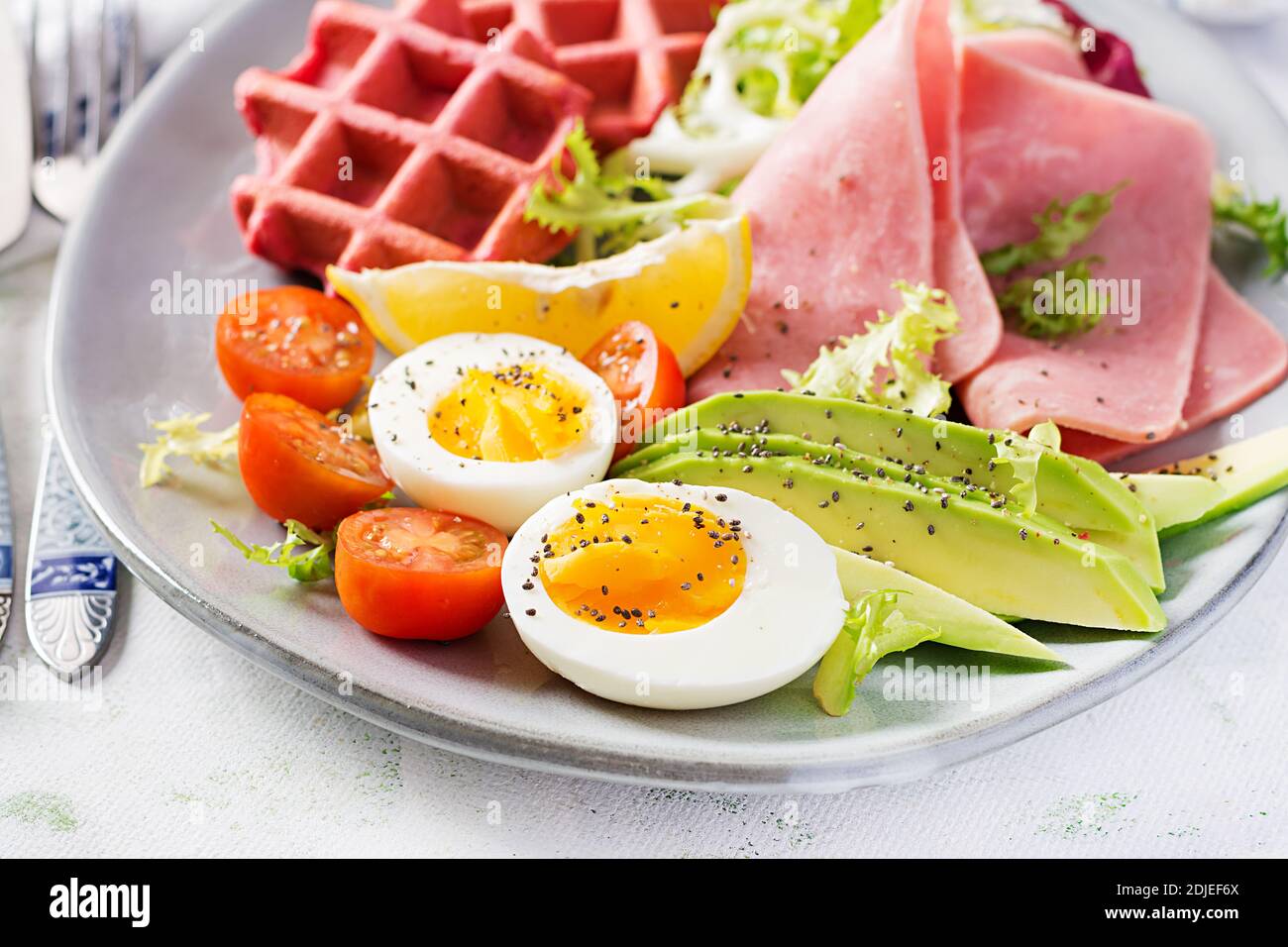 Breakfast with beetroot waffles, boiled egg, ham, tomato and slice ...