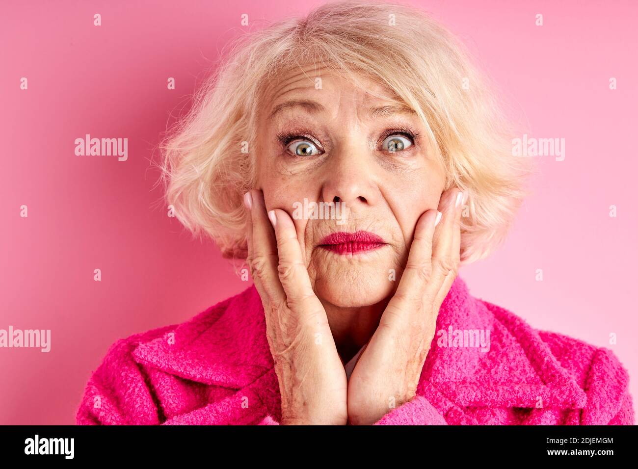 shocked mature woman in coat posing at camera, blond senior lady with ...