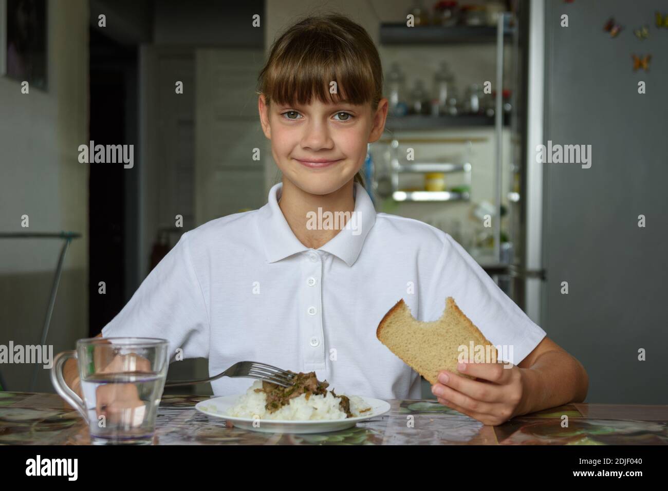 Portrait of a happy girl having dinner at the table in the kitchen ...