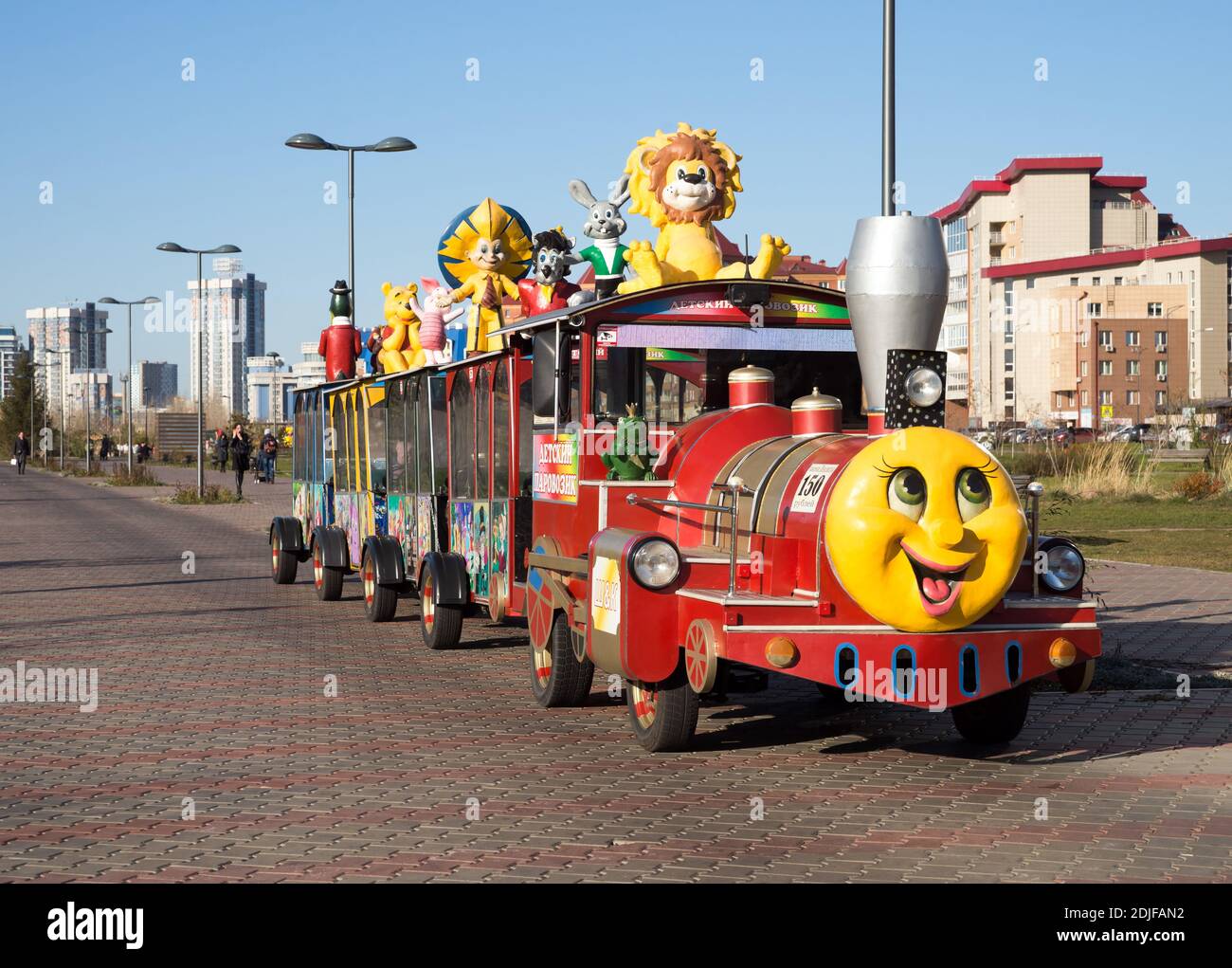 A children's steam locomotive ride on wheels drives along a paved road ...