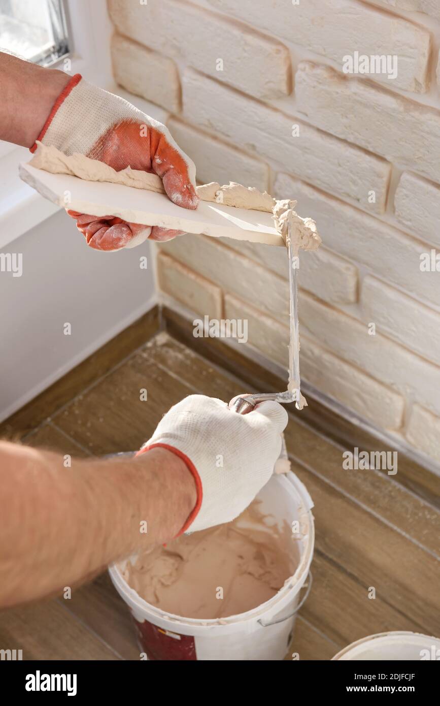 A worker is installing gypsum brick tiles on the wall Stock Photo - Alamy
