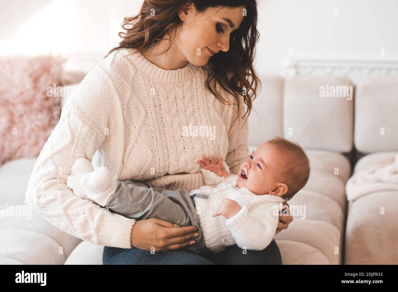 Mother holding crying baby girl waking up on her hands closeup. Woman with infant girl ...