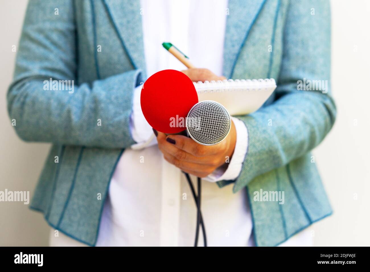 Female reporter at news conference, writing notes, holding microphone ...