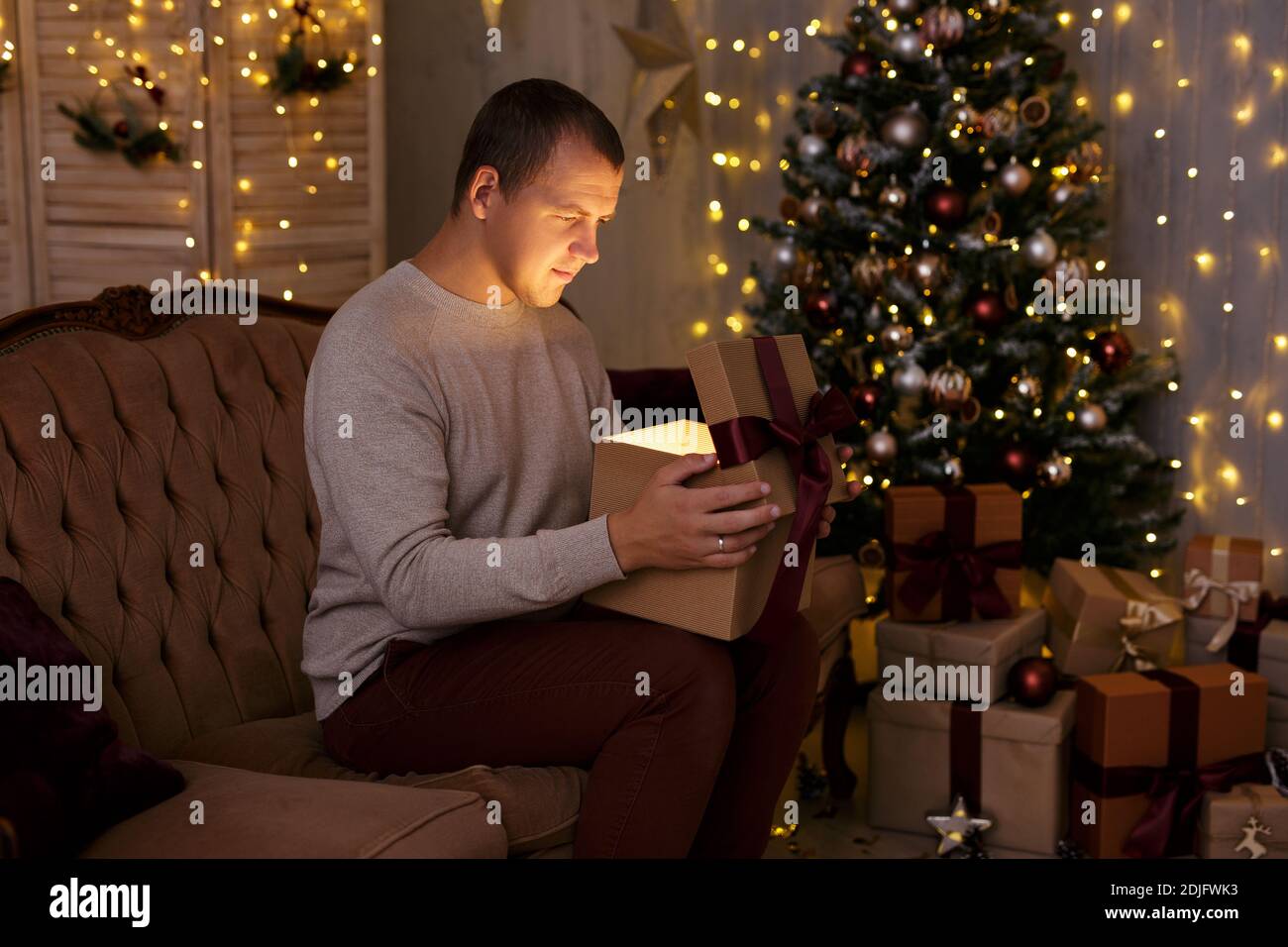 Christmas and magic concept - portrait of young man opening gift box in ...
