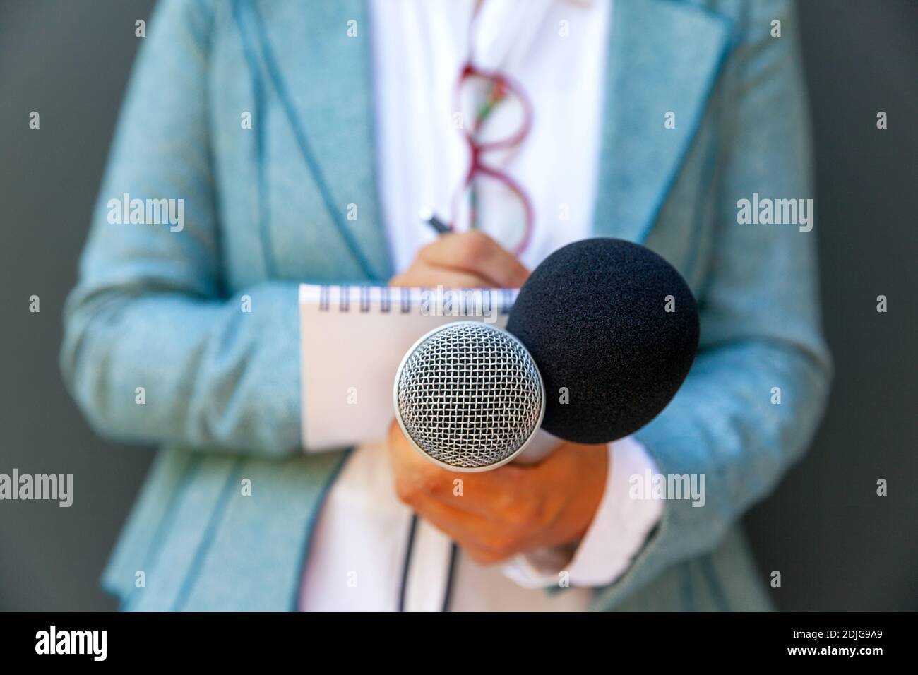 Female reporter at news conference, writing notes, holding microphone ...