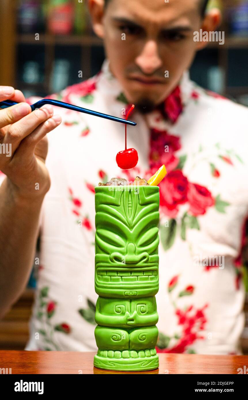 Bartender putting a cherry on a tiki cocktail Stock Photo - Alamy