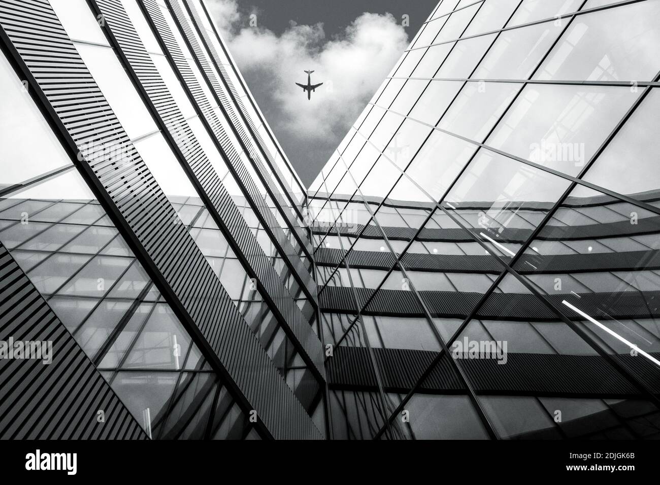 Flying airplane over modern architecture building, low angle black and ...