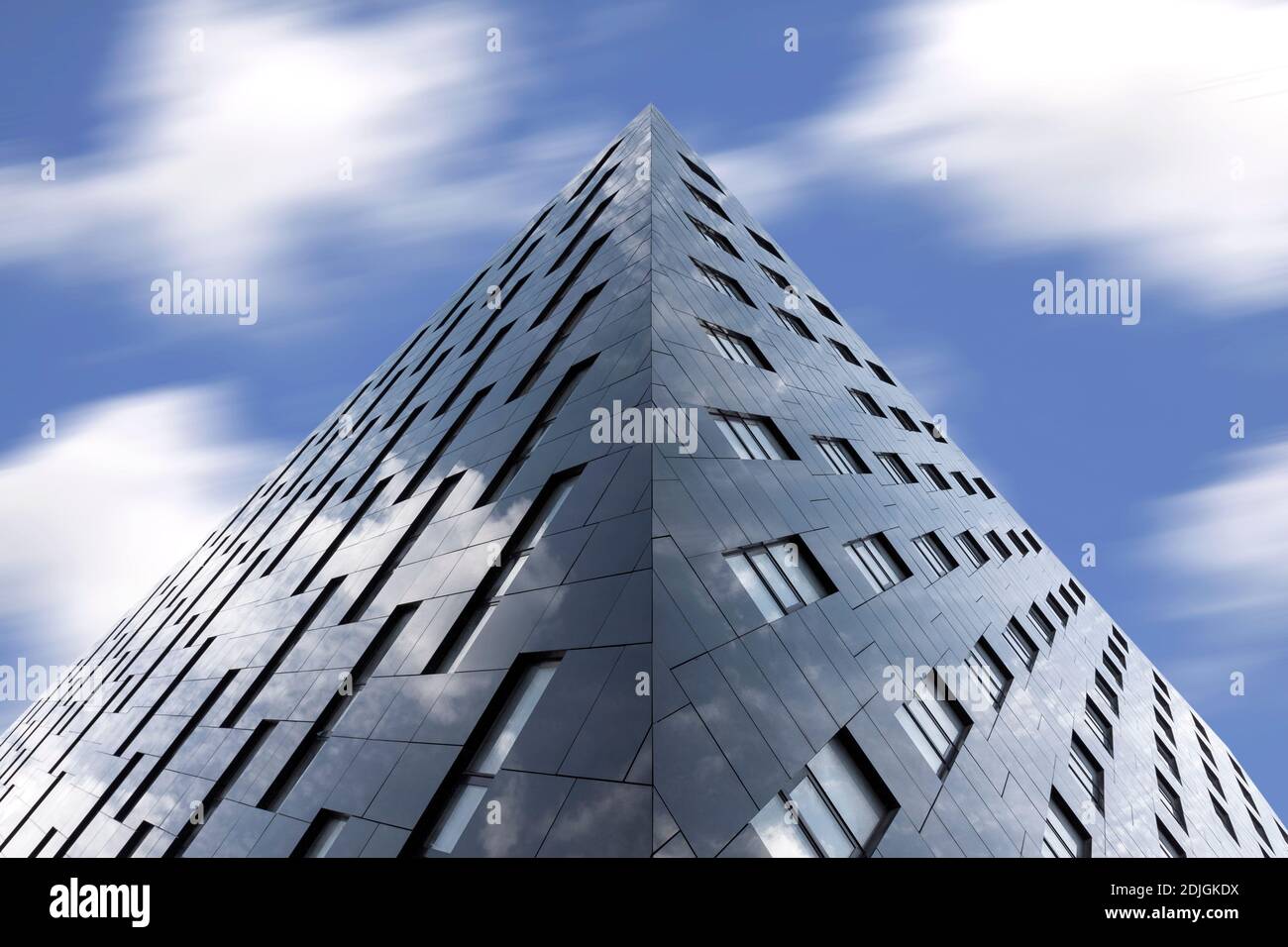 Bottom view of modern office building against blue cloudy sky with ...