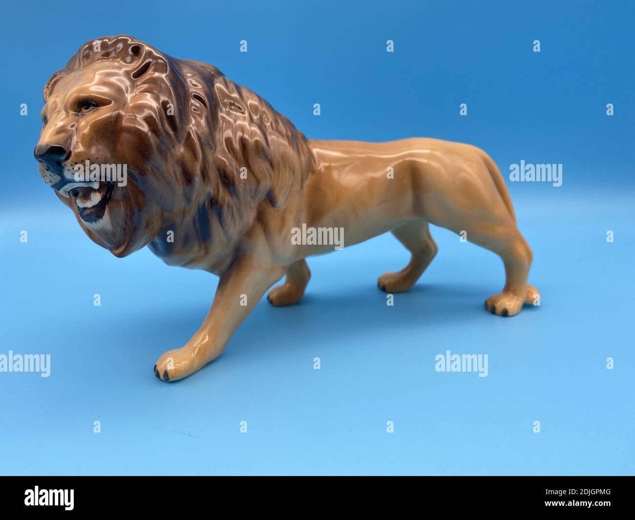 A vintage porcelain lion figurine on blue background Stock Photo - Alamy
