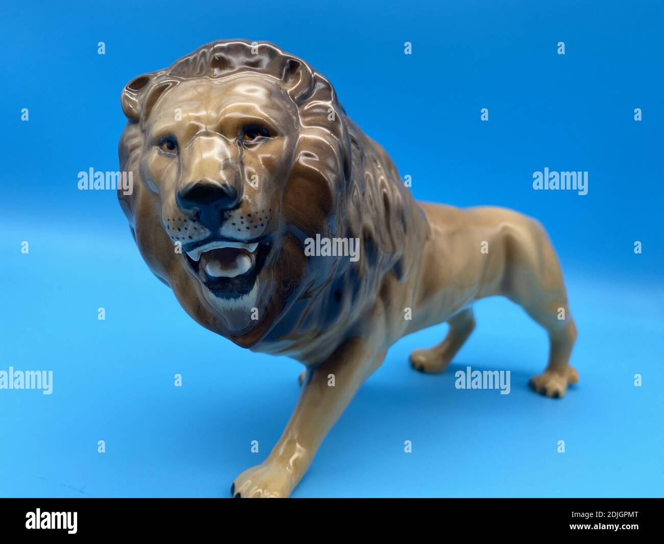 A vintage porcelain lion figurine on blue background Stock Photo - Alamy
