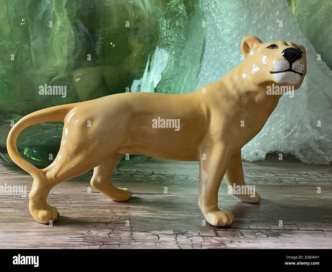 A yellow porcelain lioness figurine on green glass background Stock ...