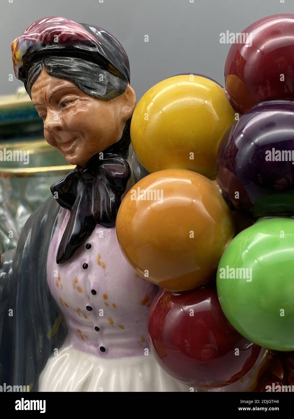 A vertical shot of an old woman porcelain figurine holding balloons ...